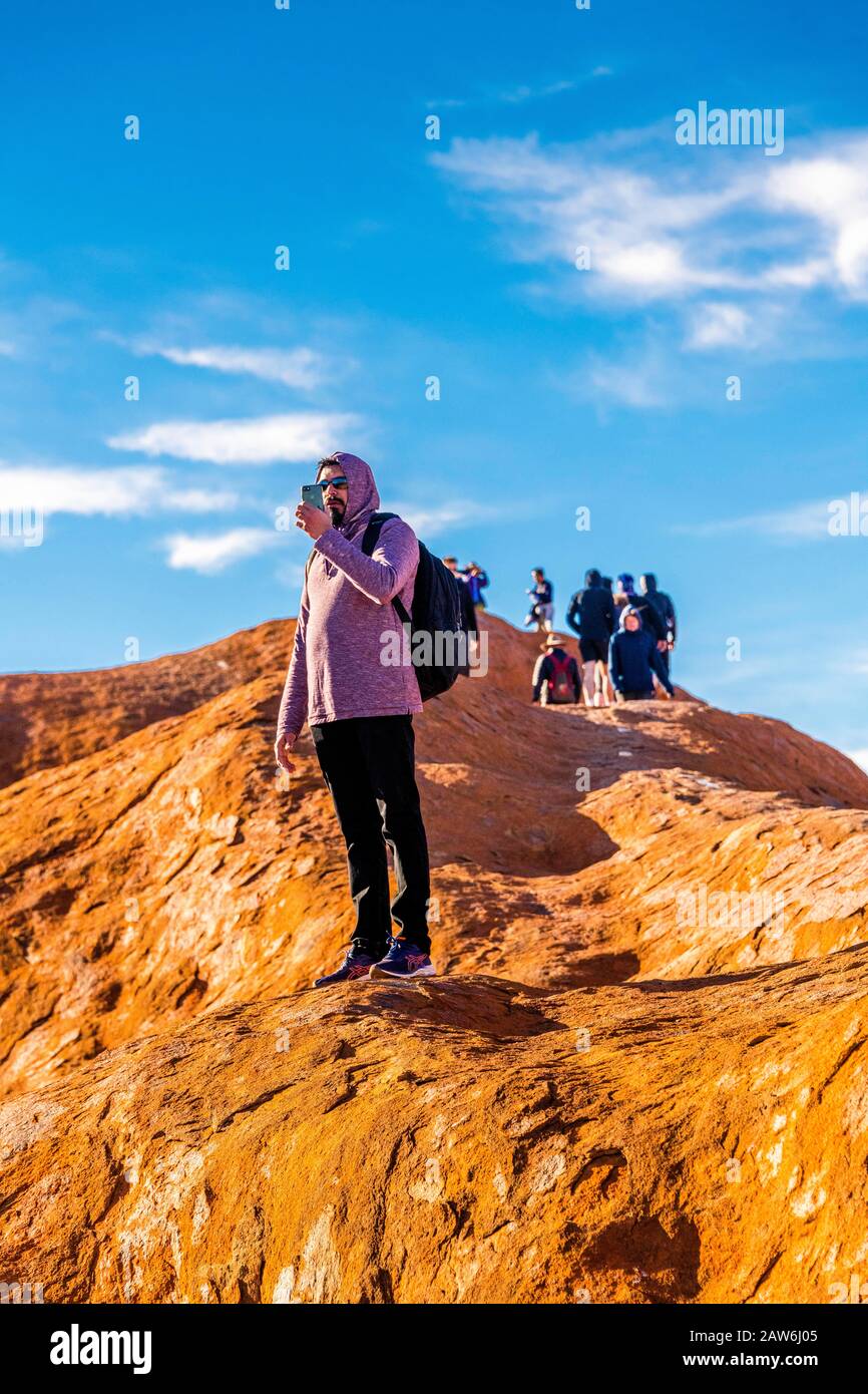 Tourists climb over the steep undulating terrain on top of Uluru ...