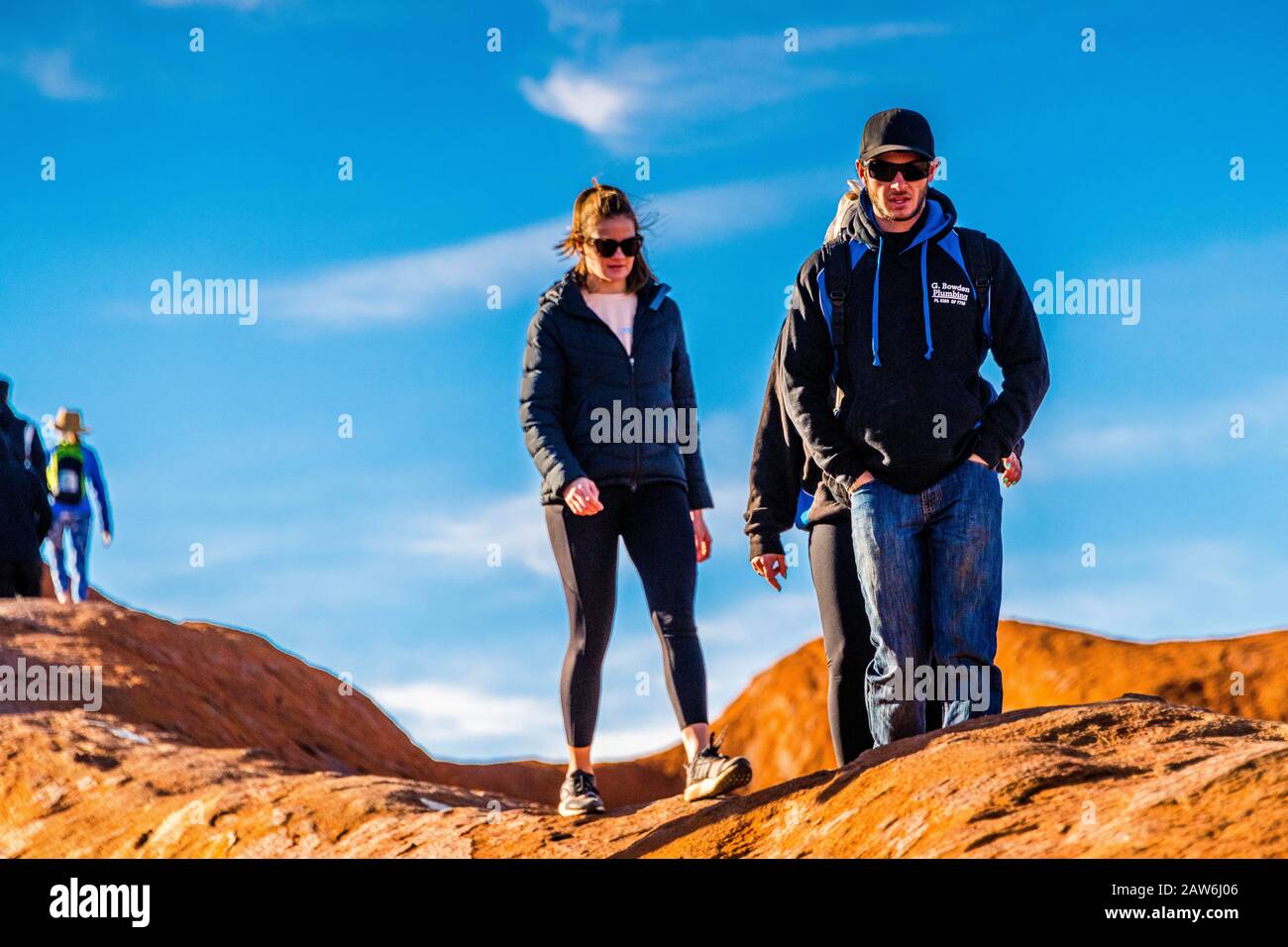 Tourists climb over the steep undulating terrain on top of Uluru ...