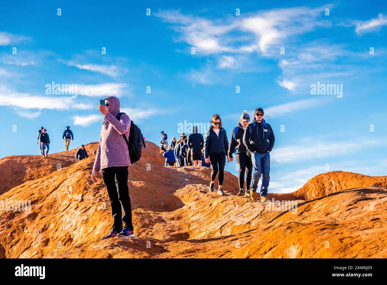 Tourists climb over the steep undulating terrain on top of Uluru ...