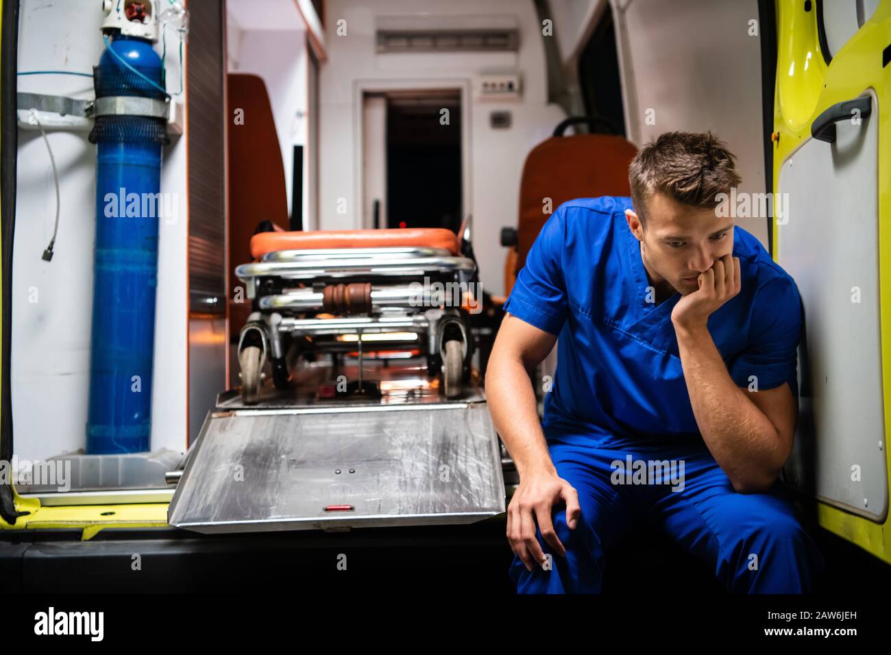 Sad corpsman sit on the ambulance car, put his head on hand and think ...