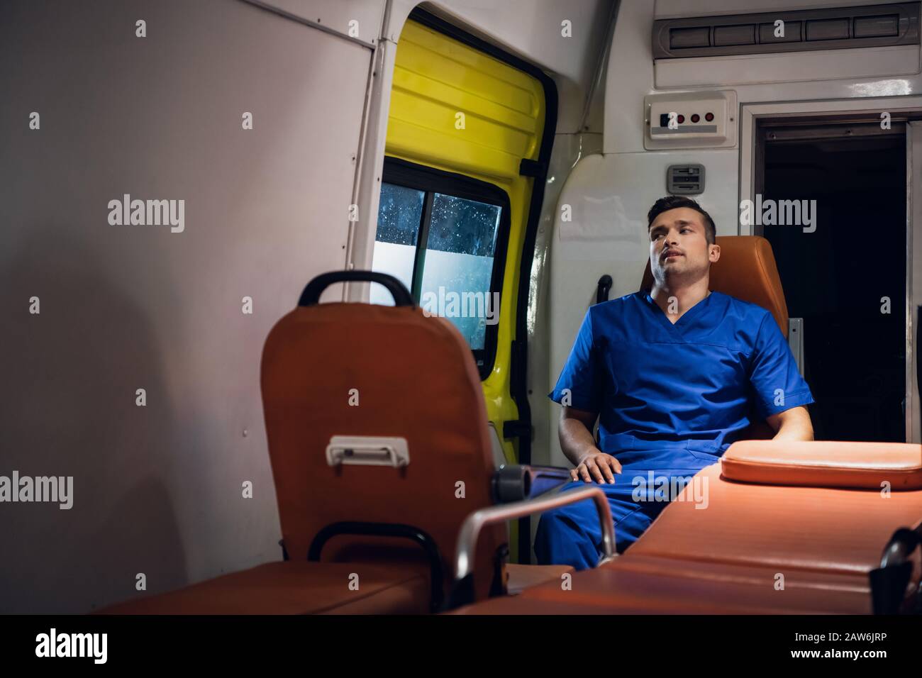 Paramedic in blue medical uniform sits in the ambulance car Stock Photo ...