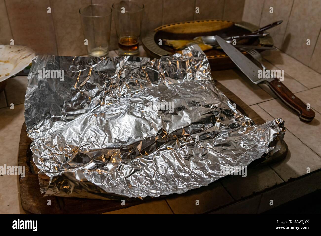 Homemade grilled dorado fish with vegetables wrapped in aluminum foil ...