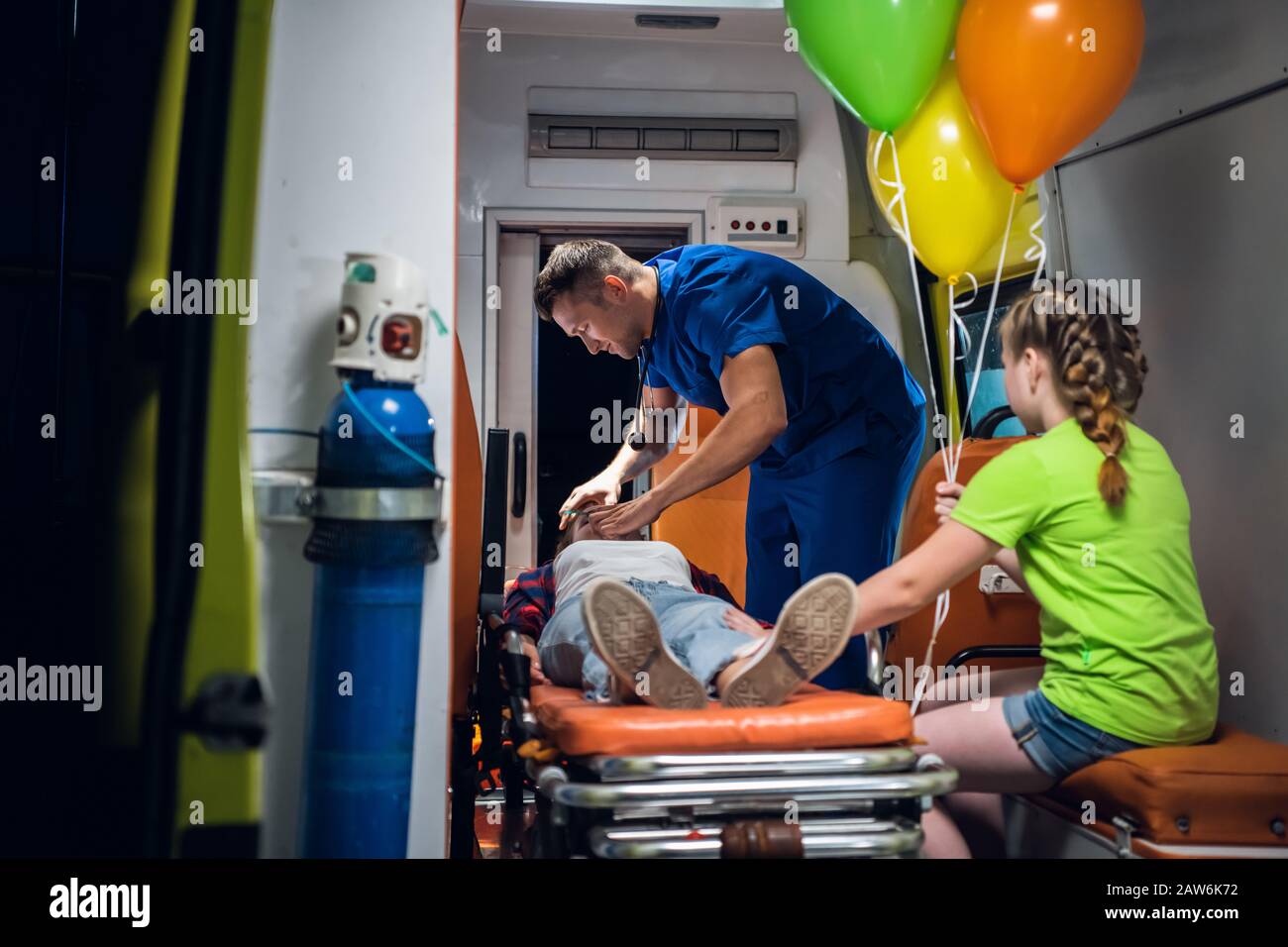 Ambulance car, corpsman in blue medical uniform regulates oxygen mask ...