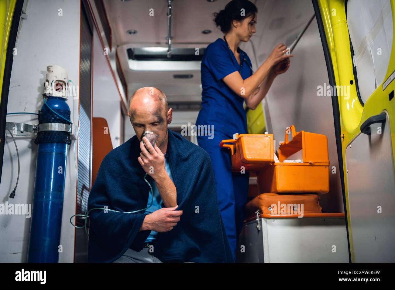 Man breathe through oxygen mask, doctor in blue medical uniform picks a ...