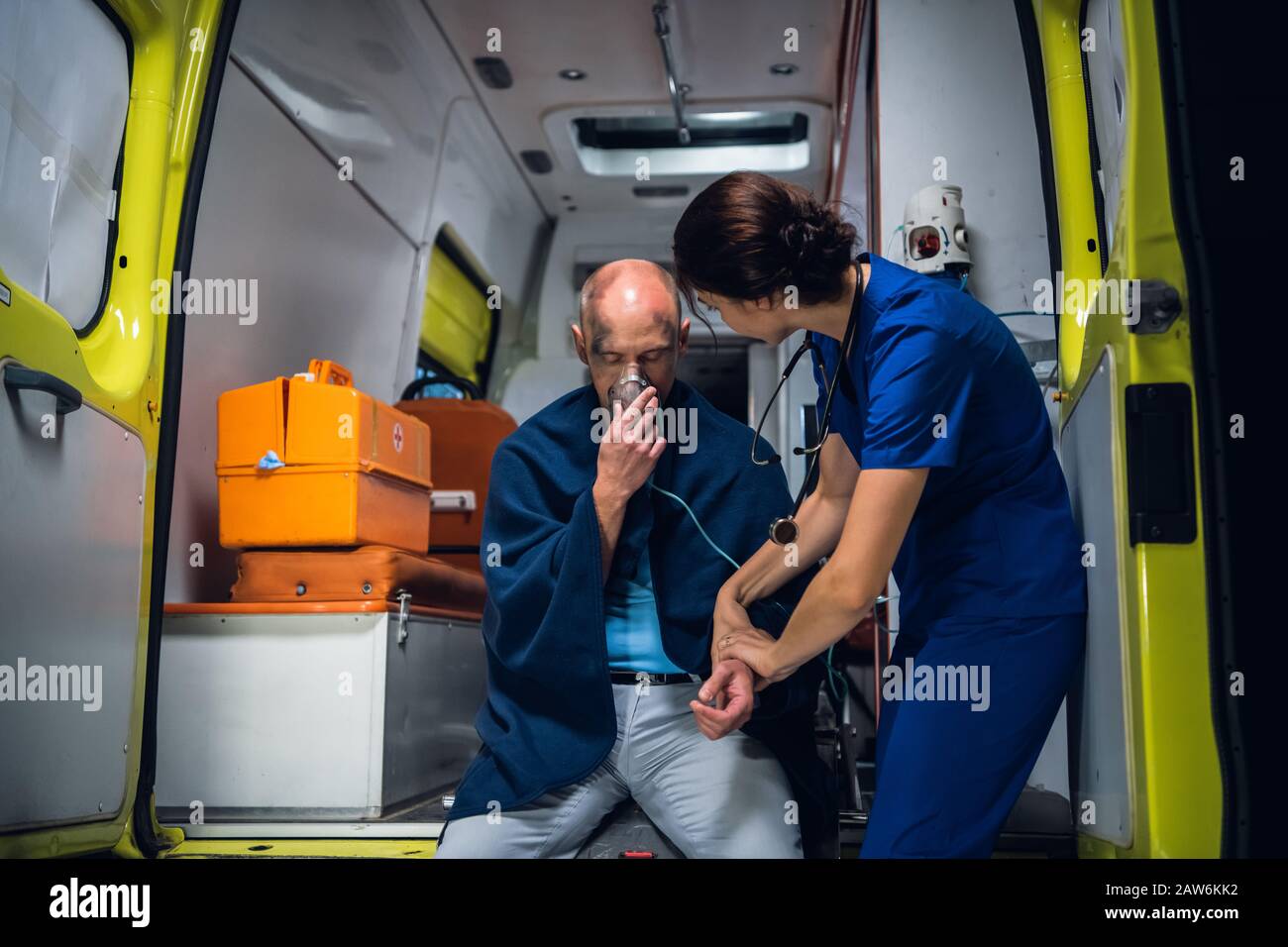 Man Sits In Blanket With Oxygen Mask Doctor In Medical Uniform Holds