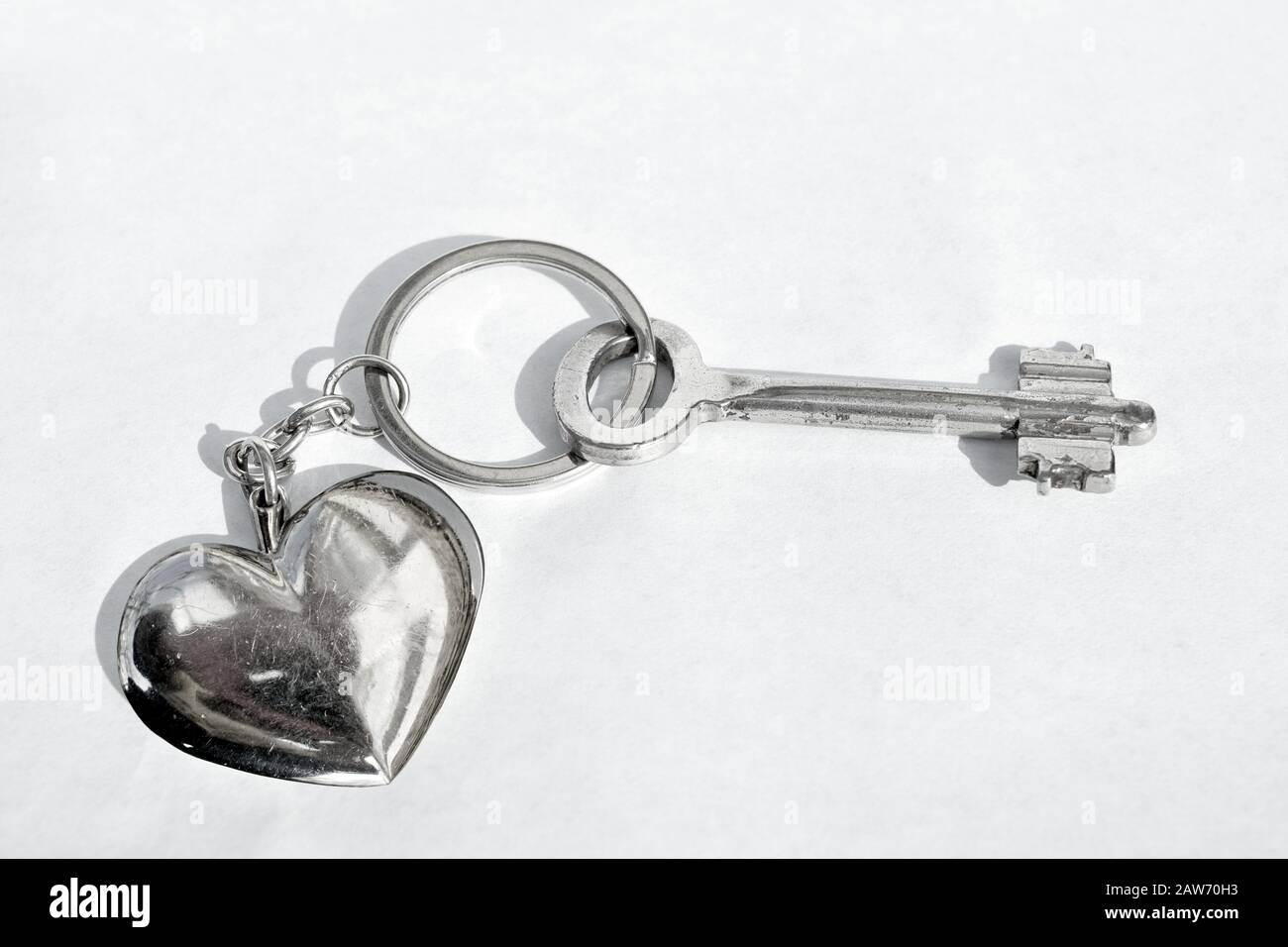 old key with metal heart on white paper background Stock Photo - Alamy