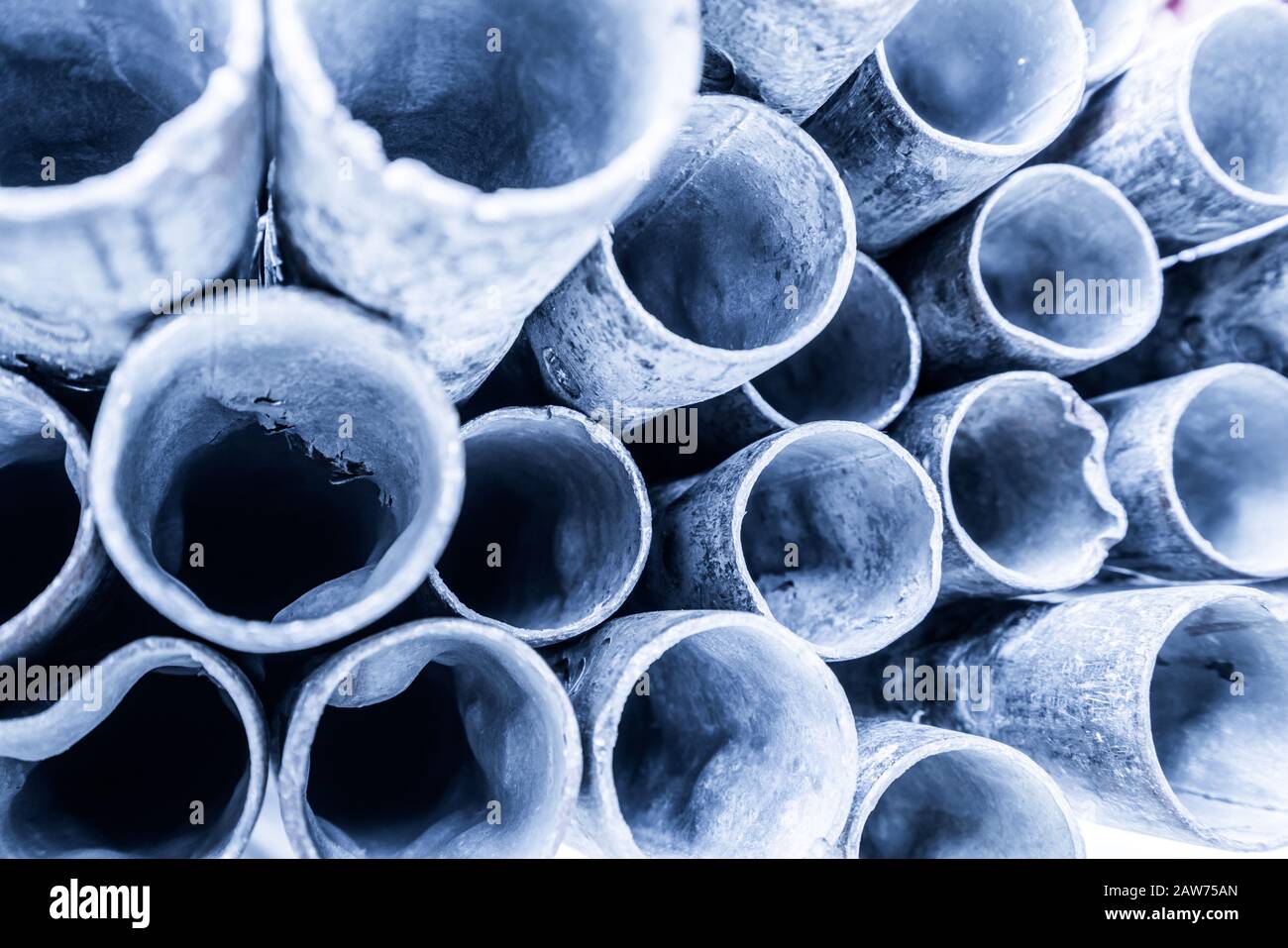 Low depth of field image of metal pipe stack in blue shade tone ...