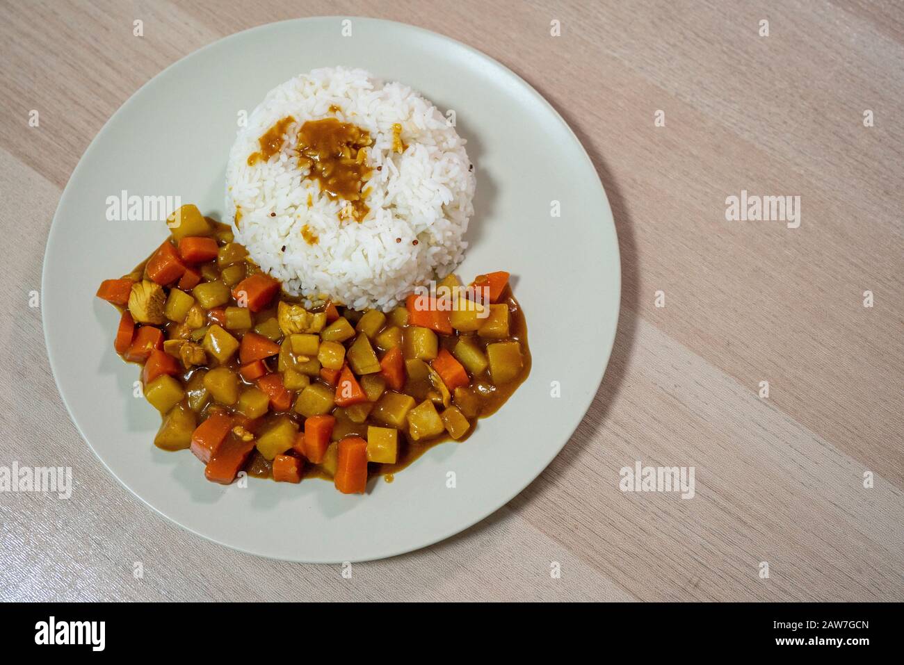 Cooked rice, curry with chicken, carrot and potato close-up on a plate ...