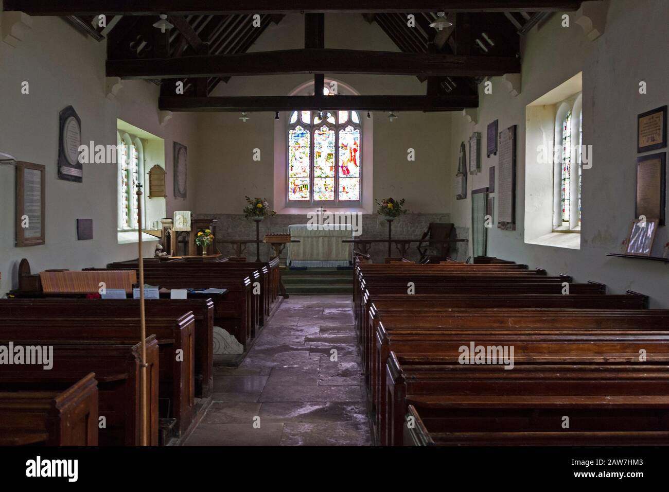 Wooden pews, altar, and east window with undivided nave and sanctuary ...