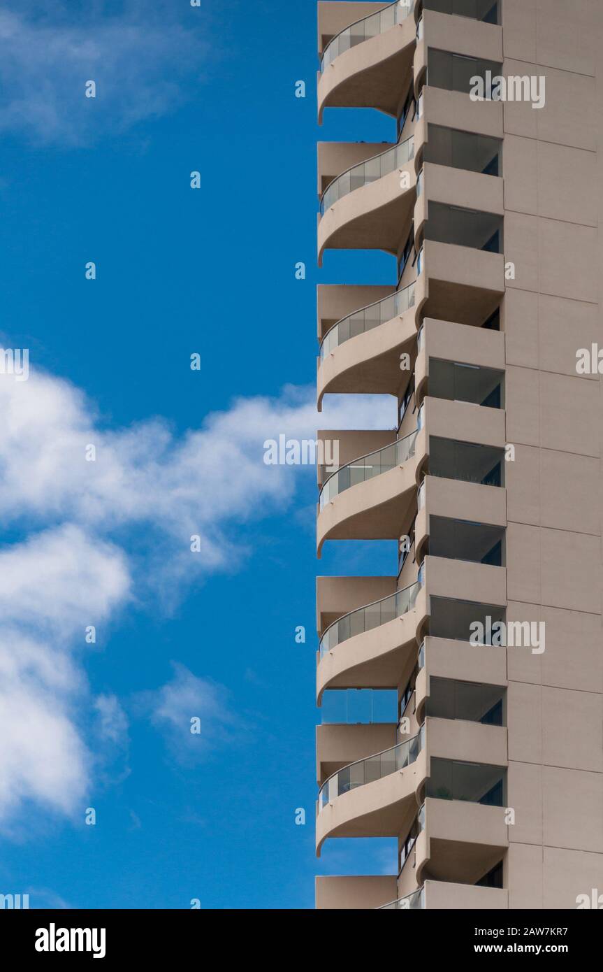 Tall skyscraper building with curvy balconies against blue sky ...