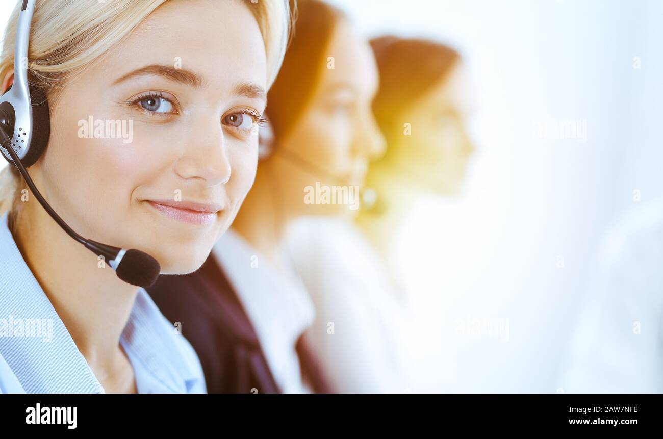Group of diverse phone operators at work in sunny office. Handsome ...