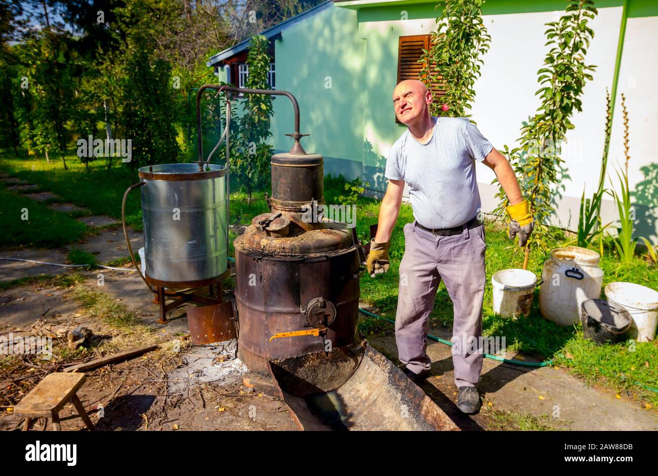 Man is manually turning lever to mix fruit marc in boiler of homemade ...