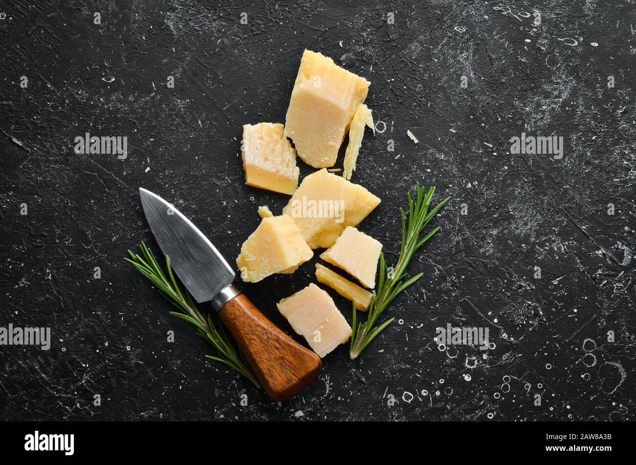 Piece of solid cheese on a black stone background. Parmesan. Top view ...