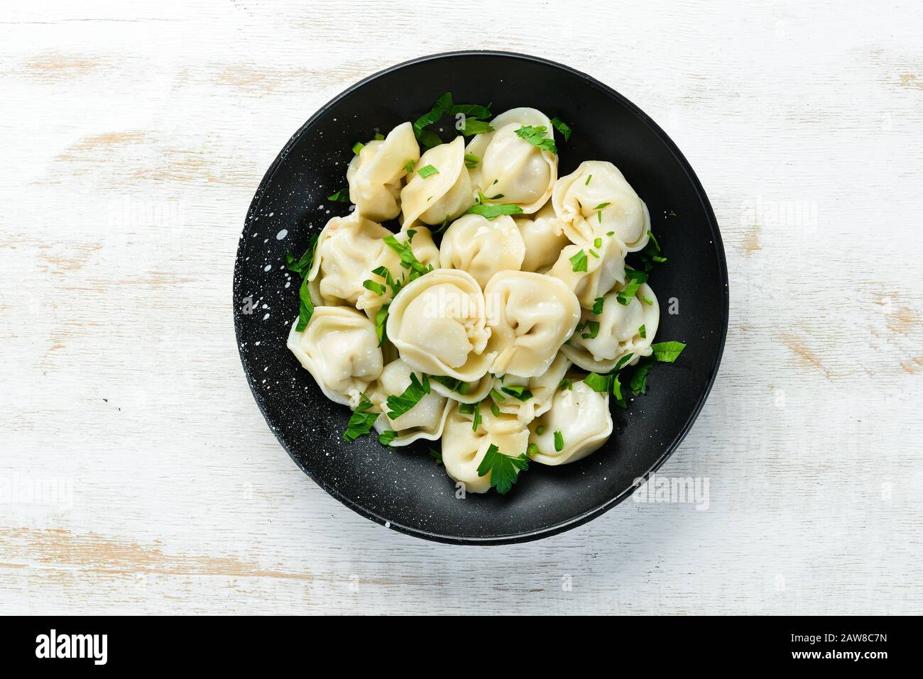 Russian pelmeni meat Dumplings with greens in a black plate. Russian ...
