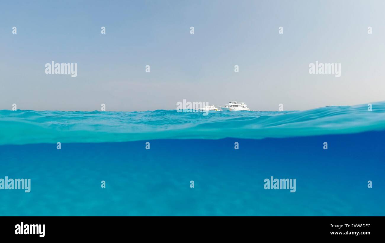 A yacht in the turquoise ocean is visible bottom, Underwater split shot ...