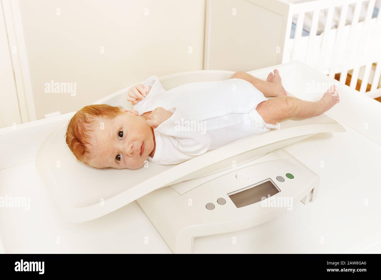 Little baby boy lay on the scale for measuring body weight at home ...