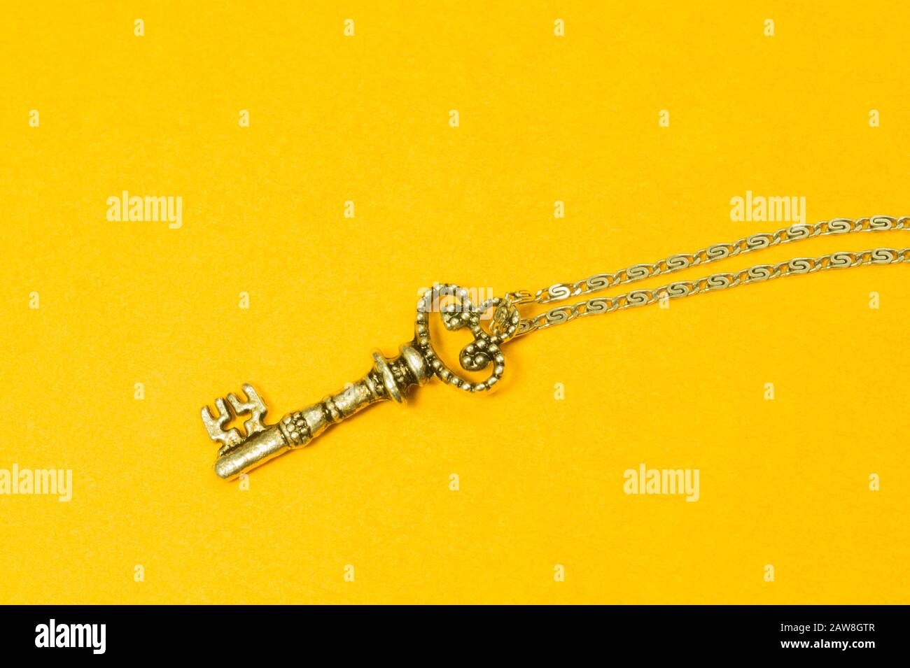 Old key with the chain isolated on yellow background. safety and ...