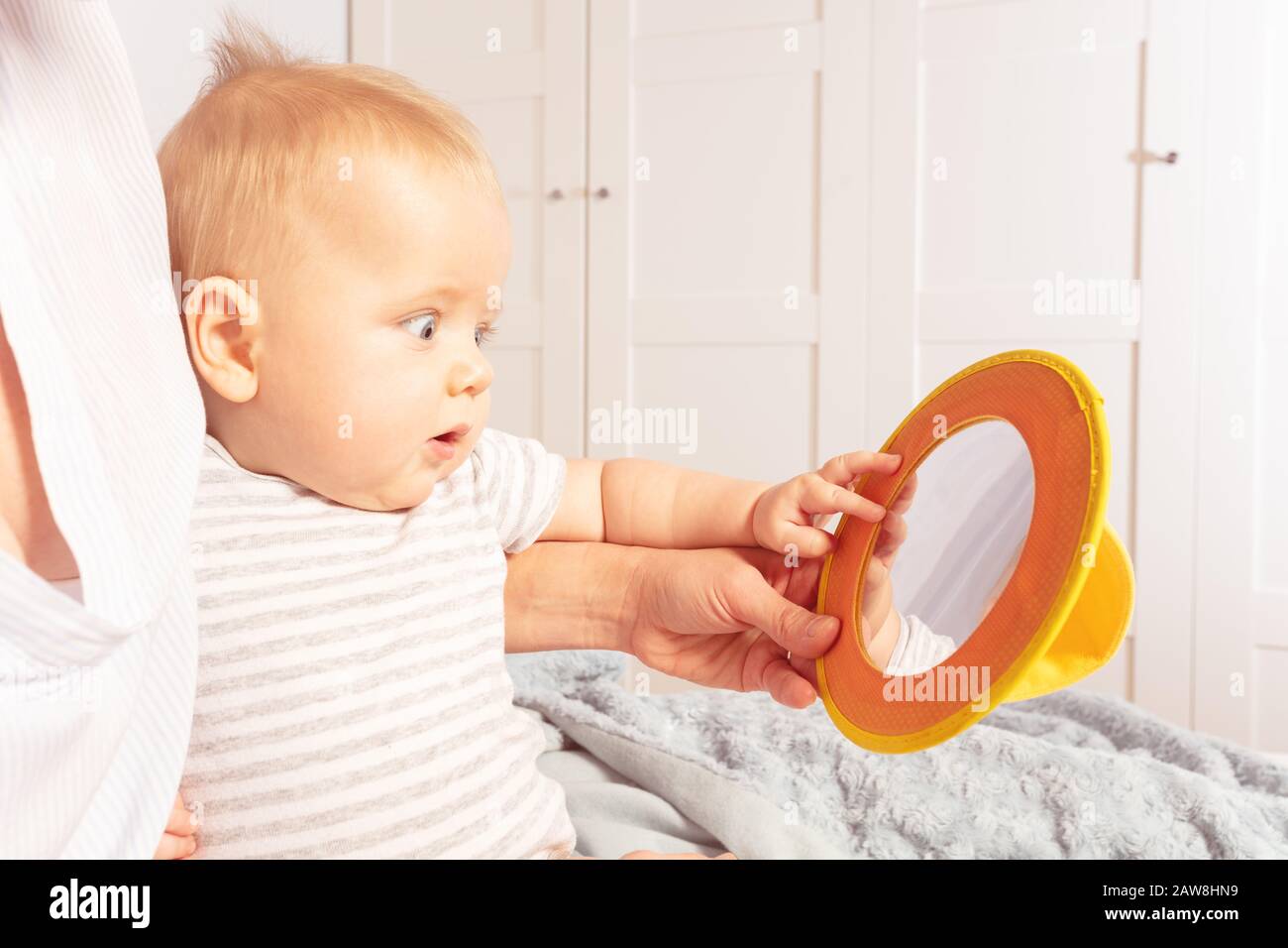 Baby infant boy look at mirror together with mom sitting in home ...