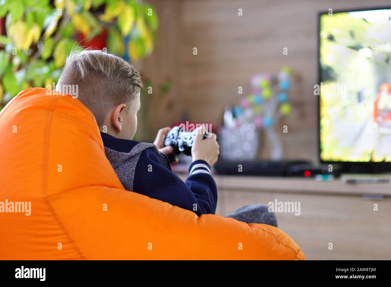 Young gamer boy playing online car racing game on new console at home ...