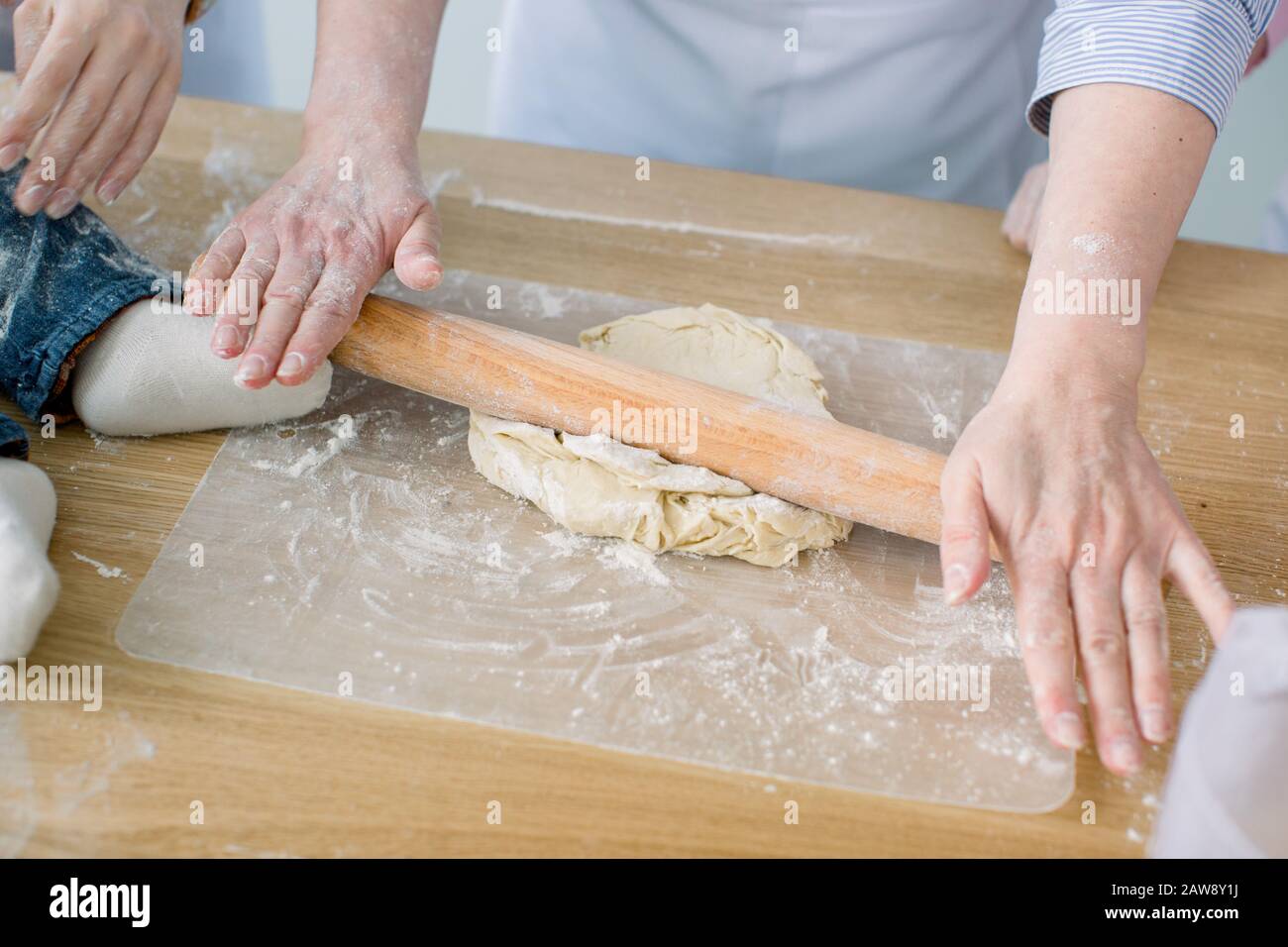 Sheeting dough. Women's hands are holding rolling pin and floured ...