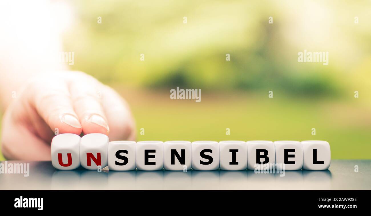 Hand turns dice and changes the German word "unsensibel" (insensitive ...