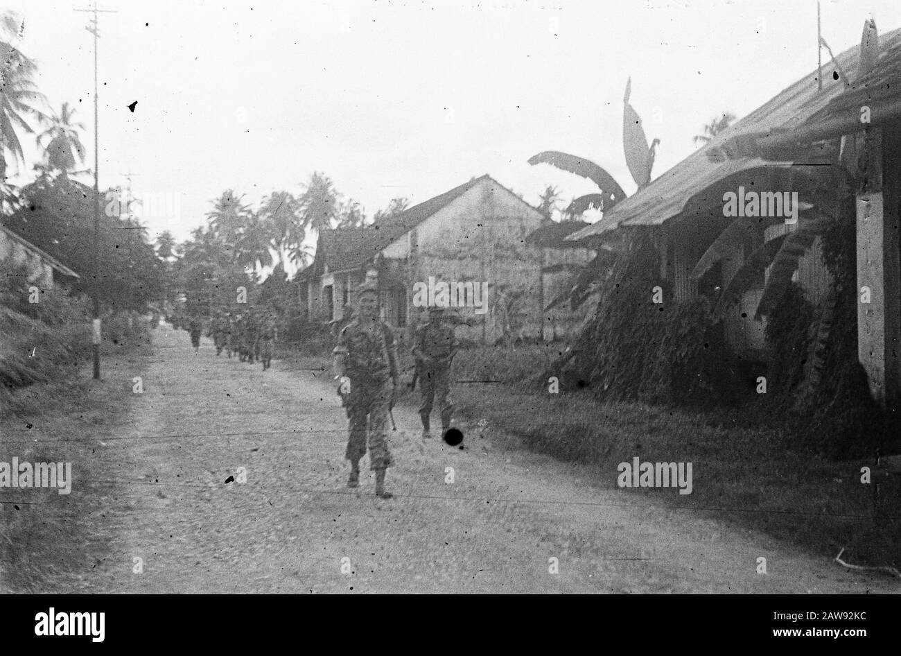 Dutch soldiers walking on a road along houses and palm trees Date: 01 ...