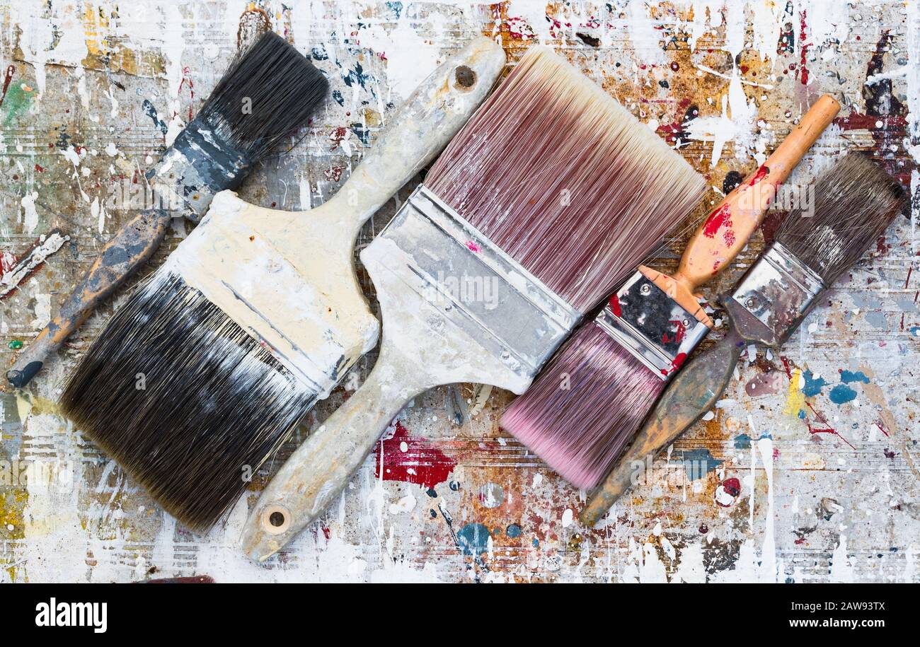 Old used paint brushes on vibrant colourful paint splattered background ...