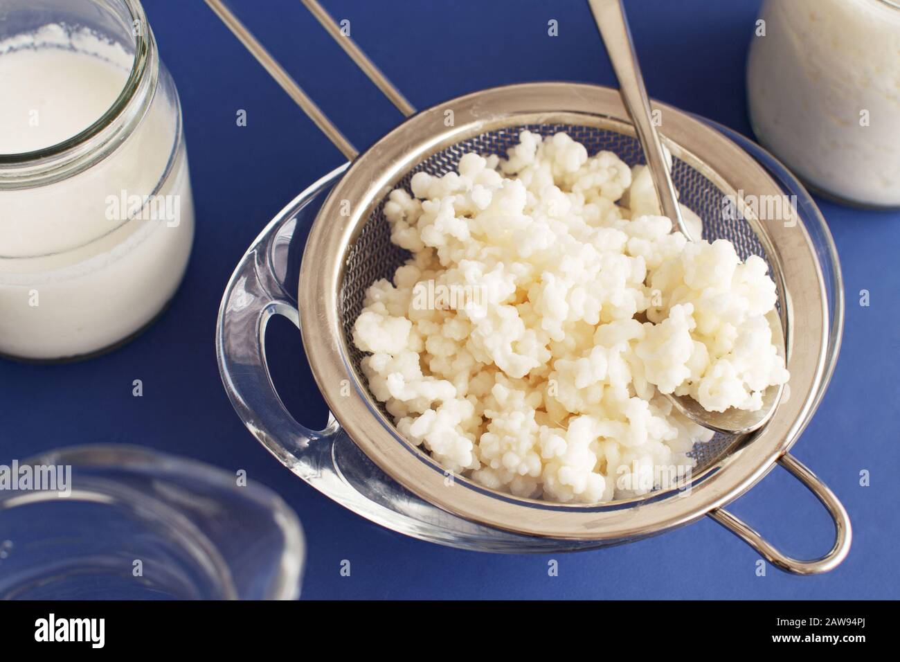 Fermented drink kefir in small bottles and kefir grains on a blue ...