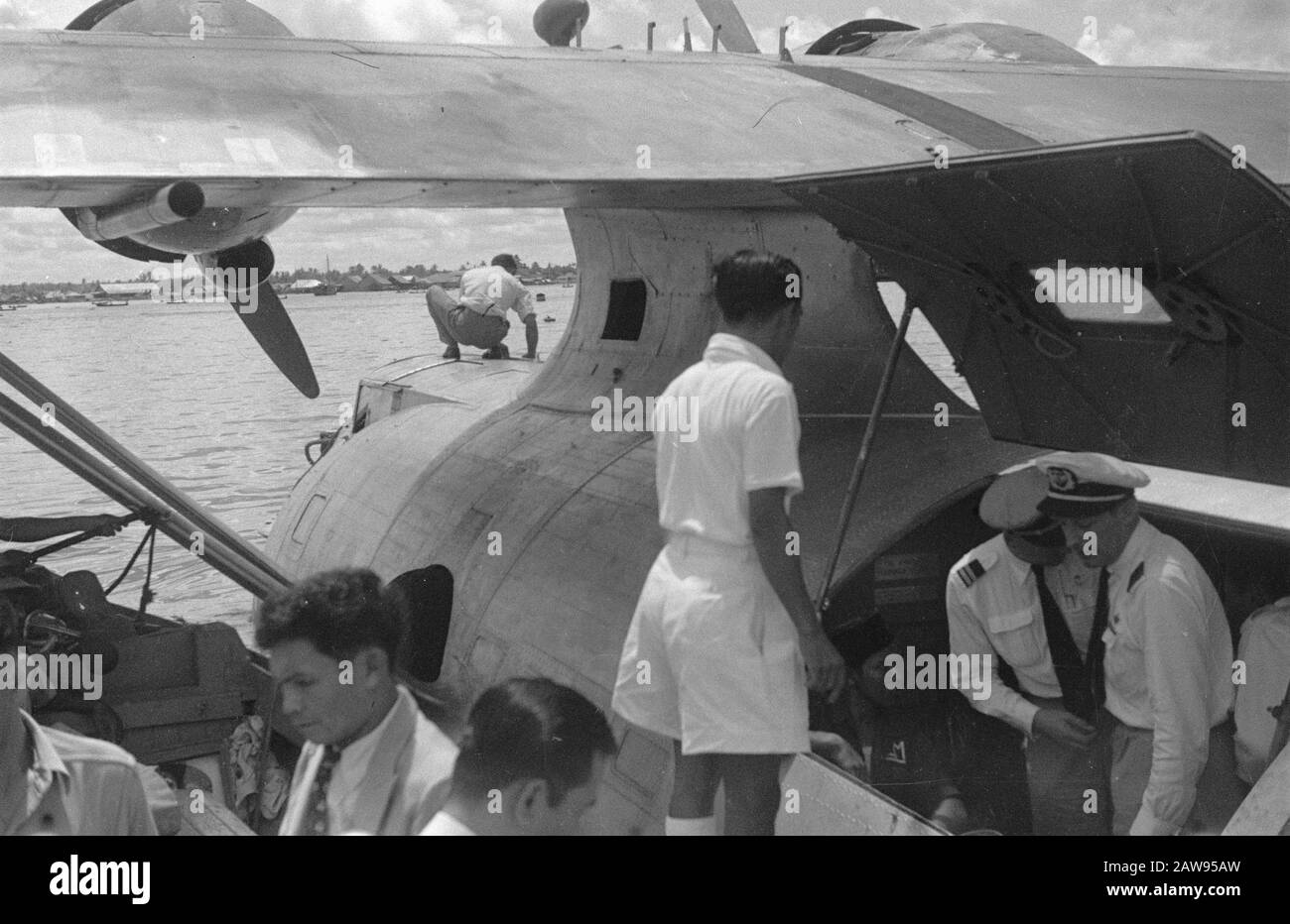 passengers board or alight a Catalina flying boat. The plane crew stand ...