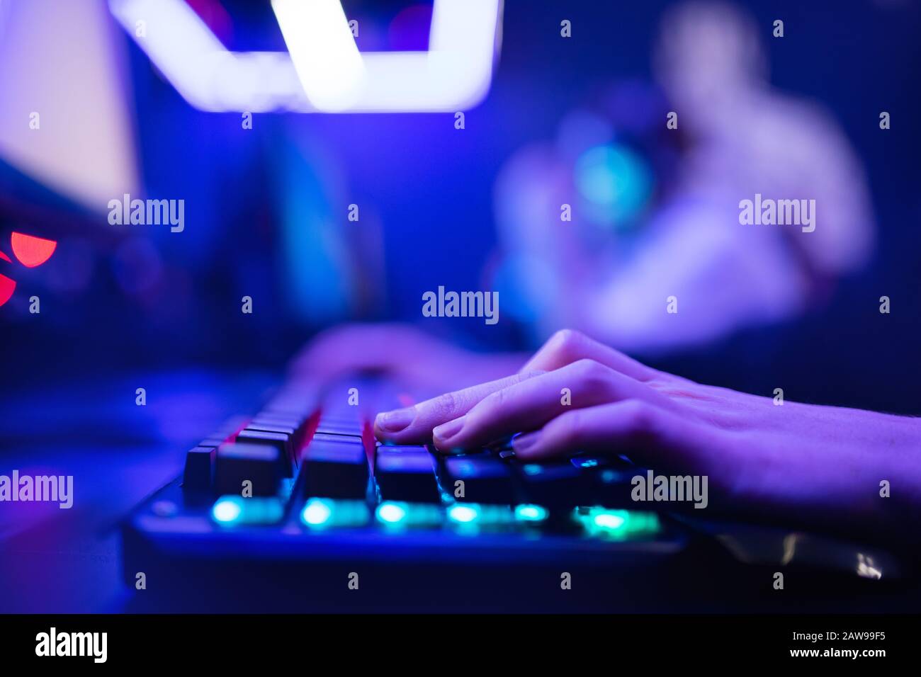 Professional online gamer hand fingers mechanical keyboard in neon ...
