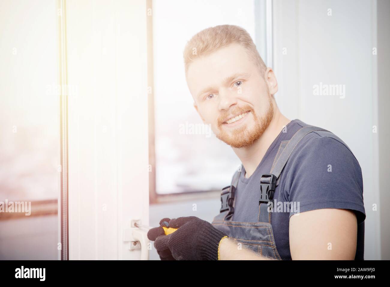 Worker man installs plastic windows and doors with double-glazed white ...