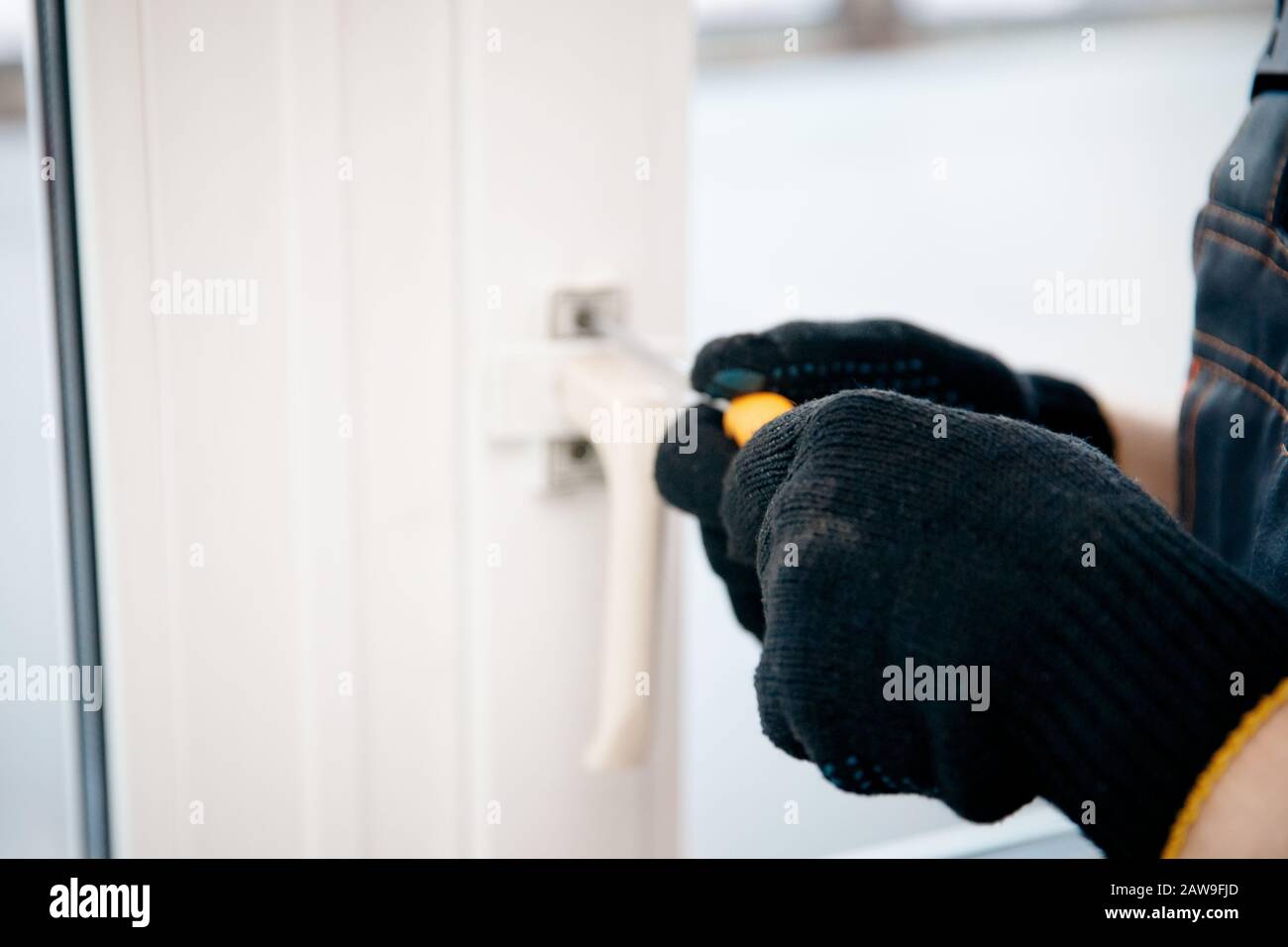 Worker man installs plastic windows and doors with double-glazed white ...