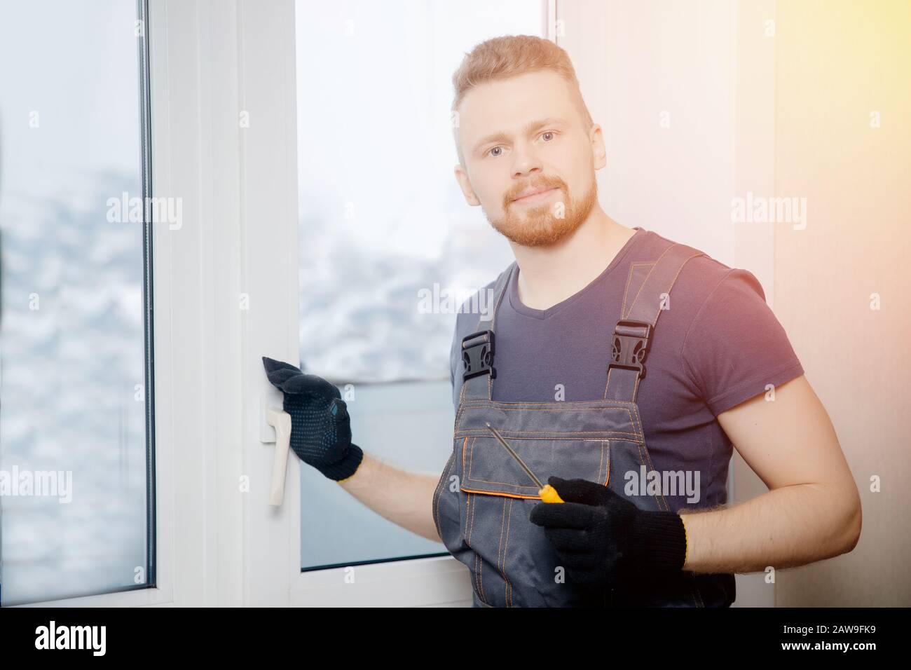 Worker man installs plastic windows and doors with double-glazed white ...