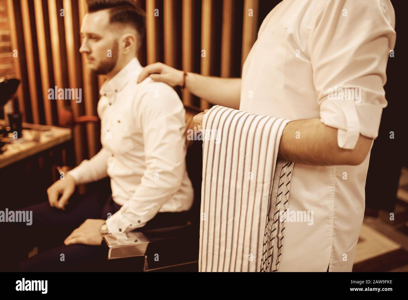 Hairdresser wagon pats in white robe and towel on hands shoulder of ...