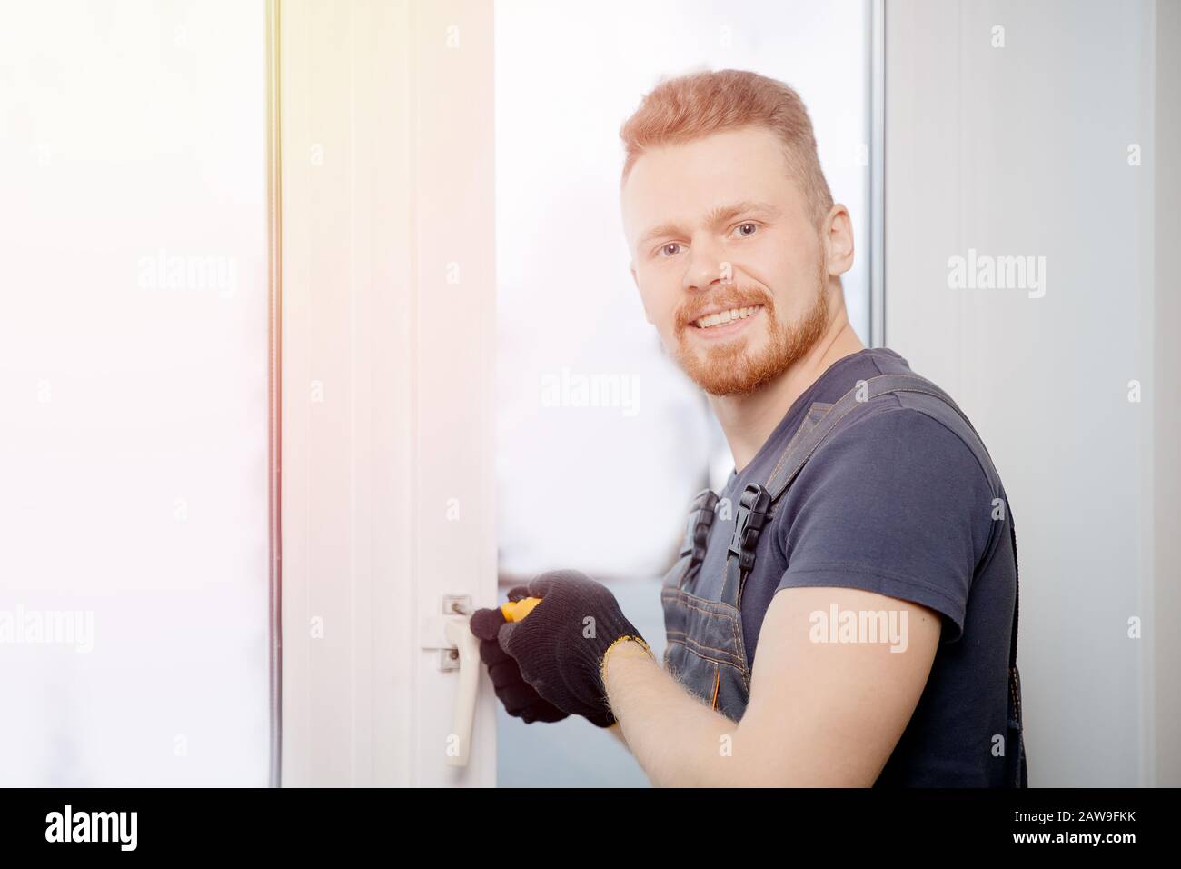 Worker man installs plastic windows and doors with double-glazed white ...
