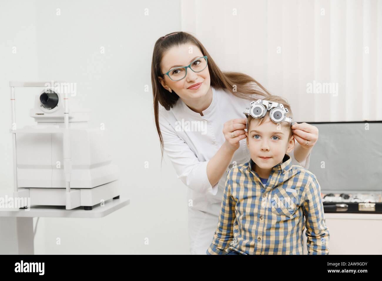 Young girl doctor holding up patient special glasses for eye tests and ...