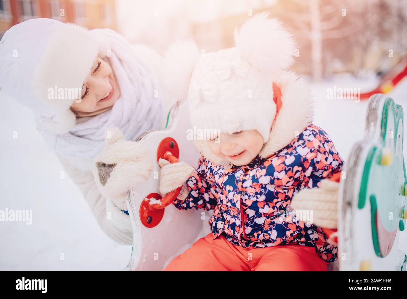 Beautiful mom in white robe. Games on children swing with little happy ...