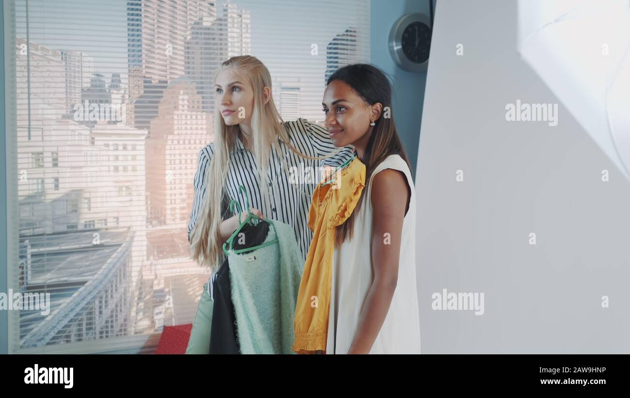 Female fashion stylist proposing black model different clothes for ...