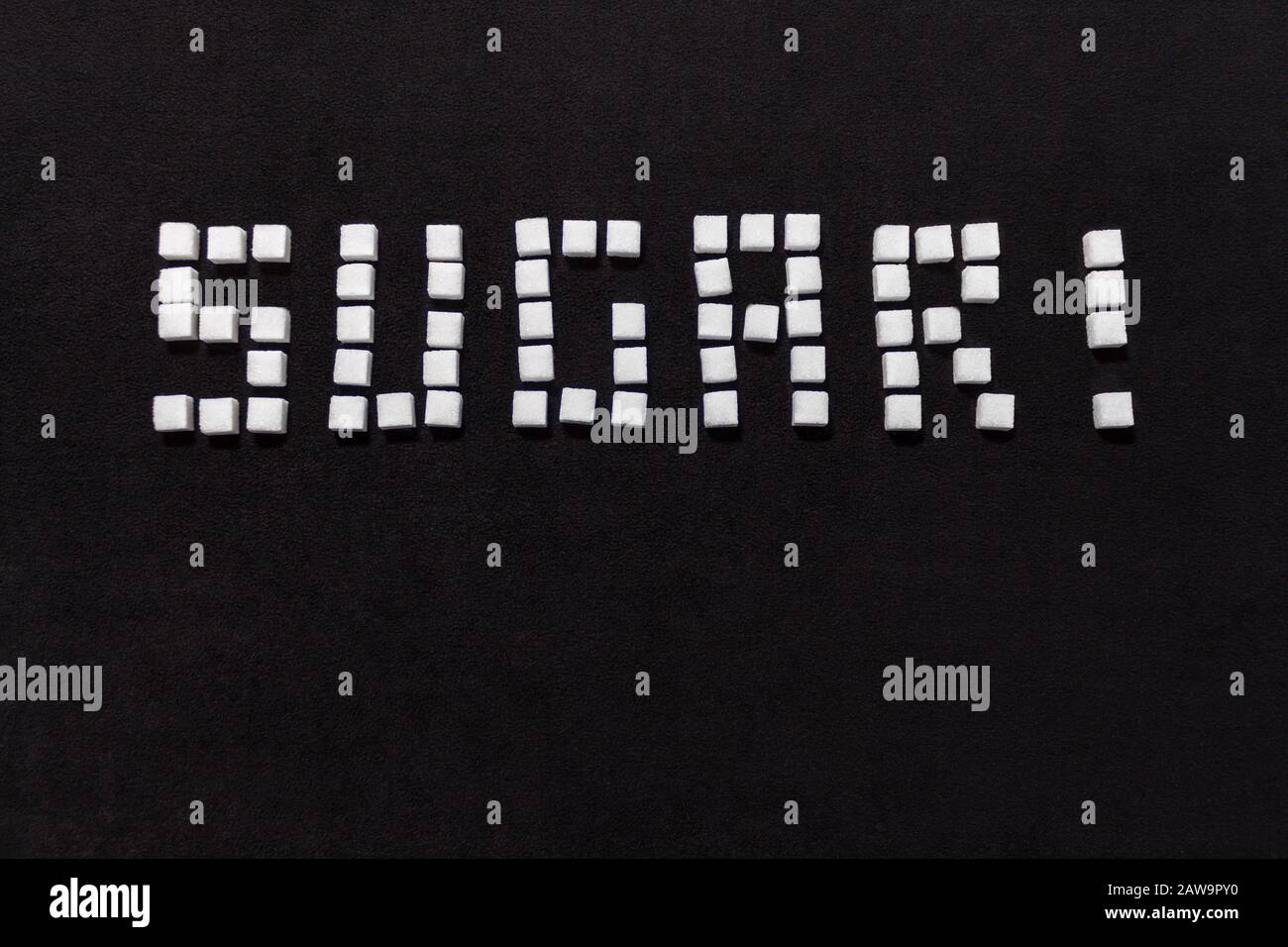 The word sugar in arranged from sugar cubes in English on a black ...