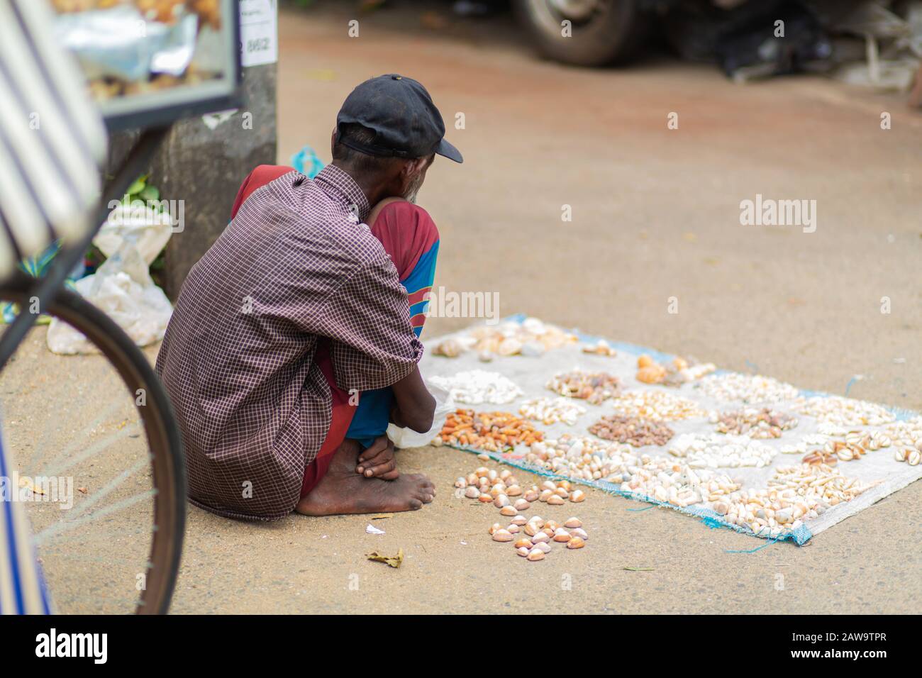 A street vendor sells his goods by laying them on the floor. Dirt and ...