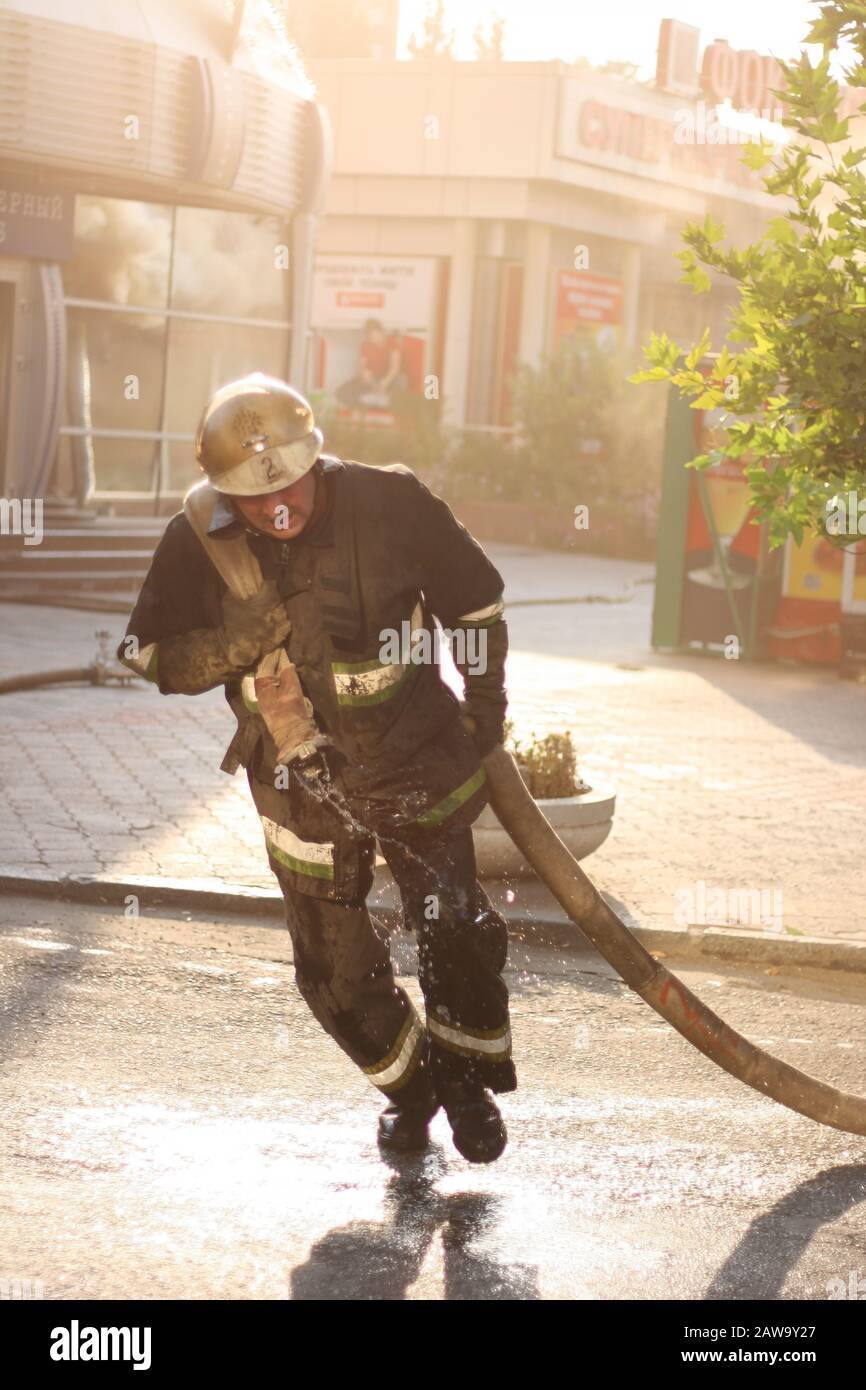 Firefighters connect hoses to a hydrant on the street near a burning ...
