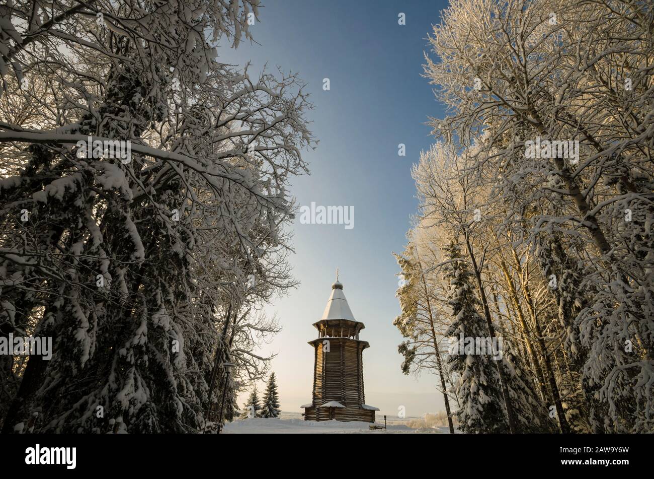 Wooden bell tower in a snowy forest. Forest path to the wooden tower ...