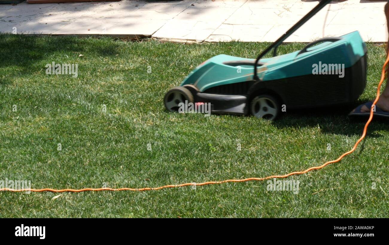 Man cutting the grass with lawn mower. Gardening activity Stock Photo ...