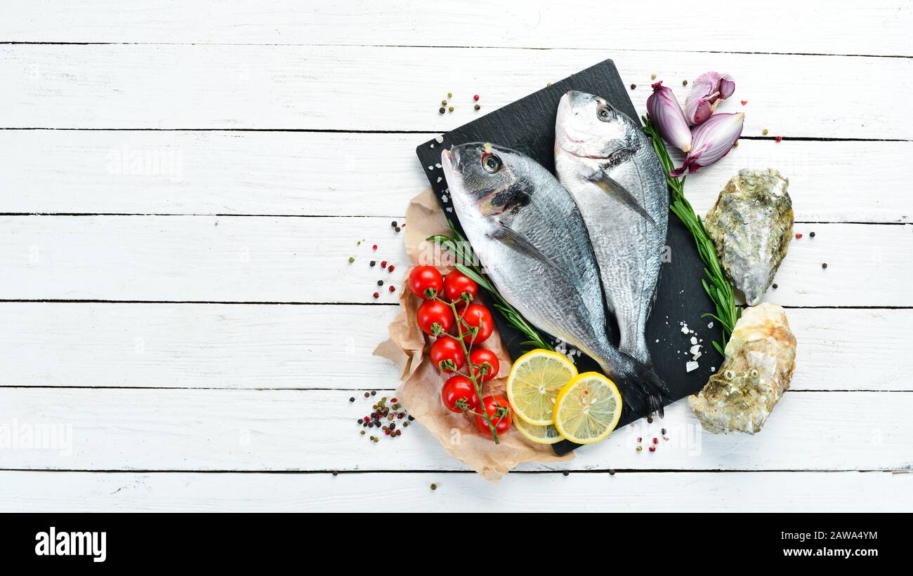 Raw fish with lemon and spices on a white background. Fish dorado. Top ...