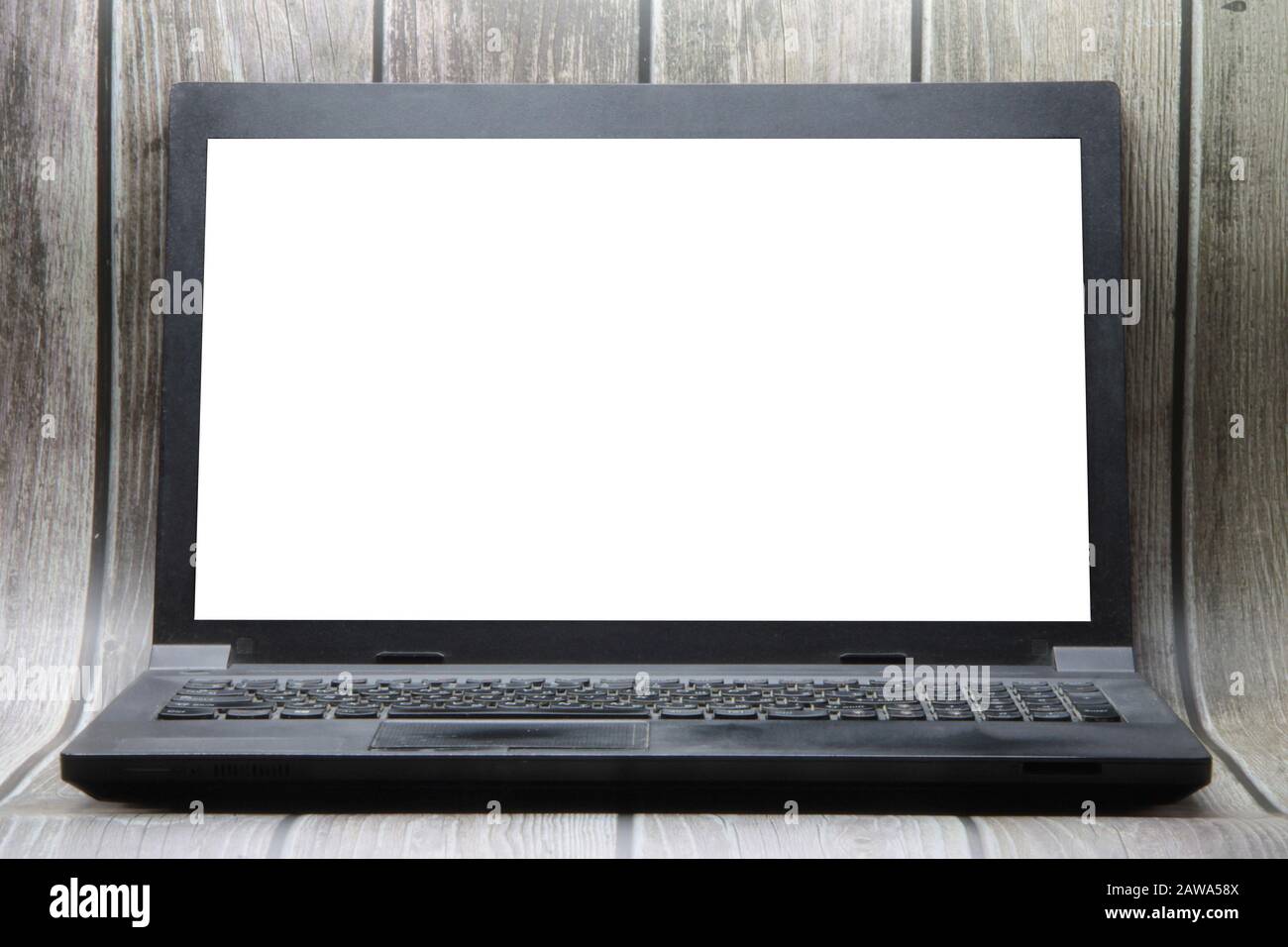 A laptop with a white screen stands on the background of wooden boards ...