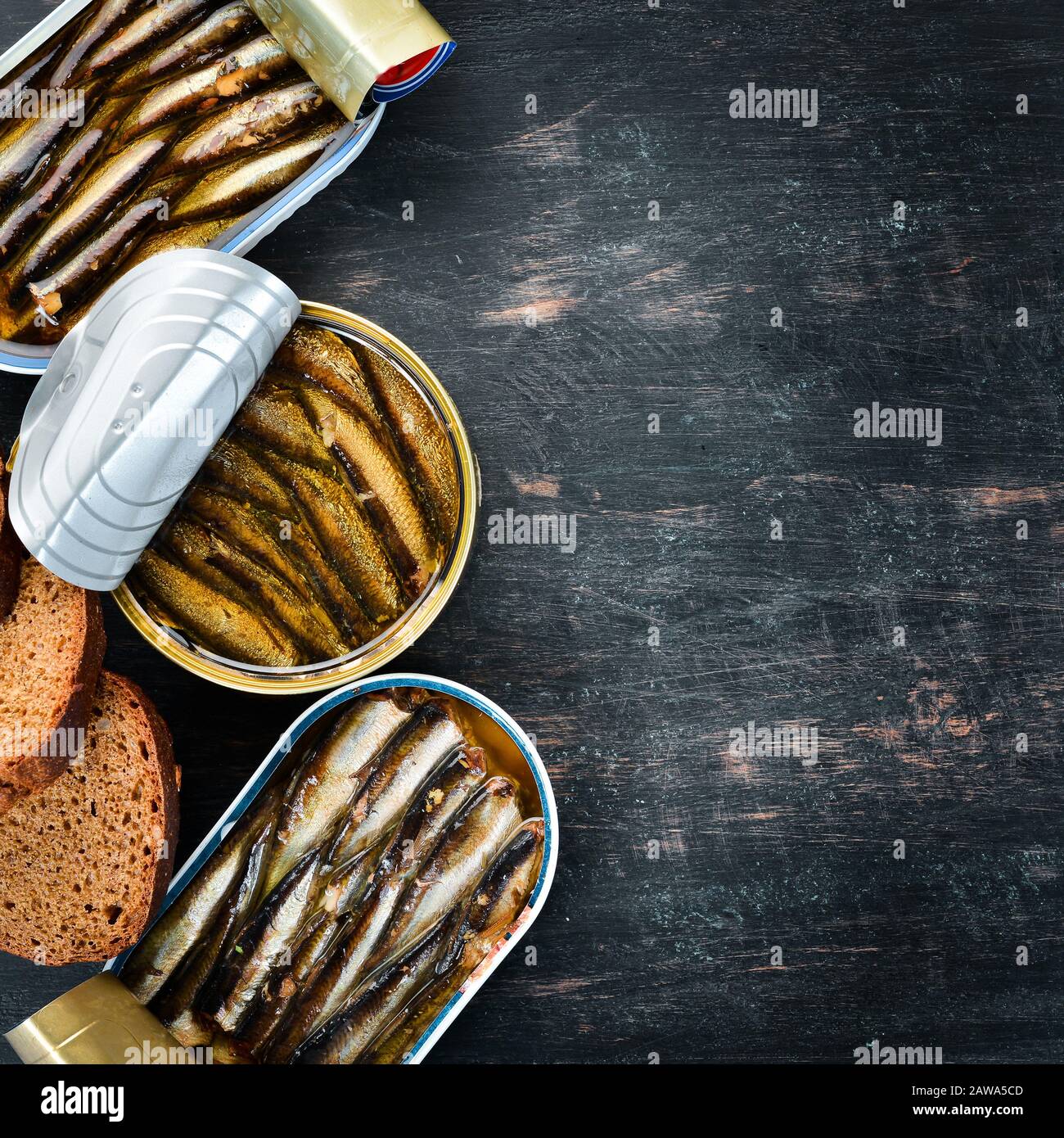 Smoked Sprats in a jar. Fish. On a black background. top view. Free ...