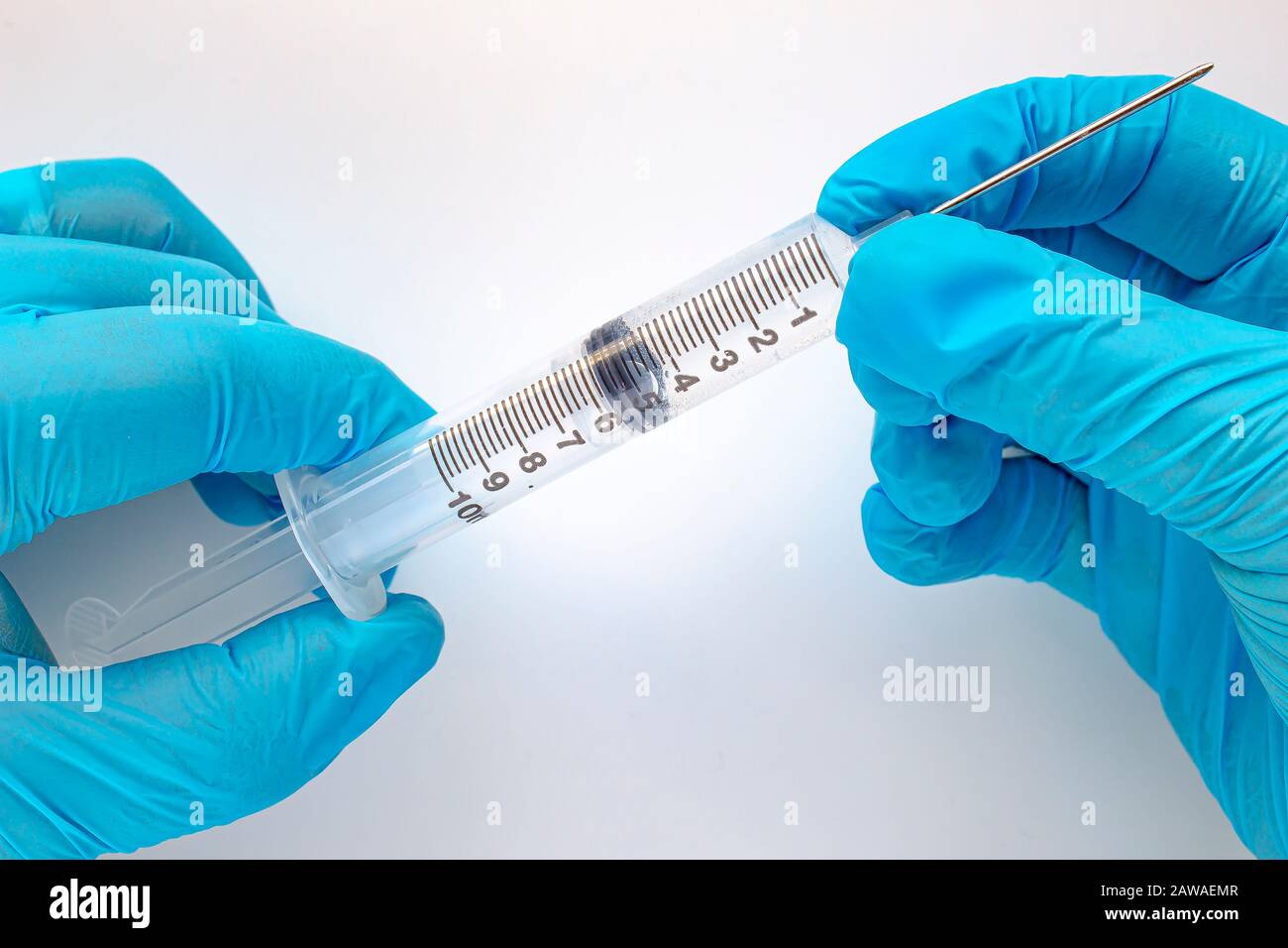 Doctor or nurse with a full syringe in blue gloves on a white ...