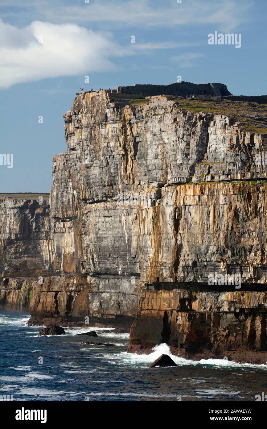 Tourist standing on the edge of the cliffs in Dun Aengus fort on ...