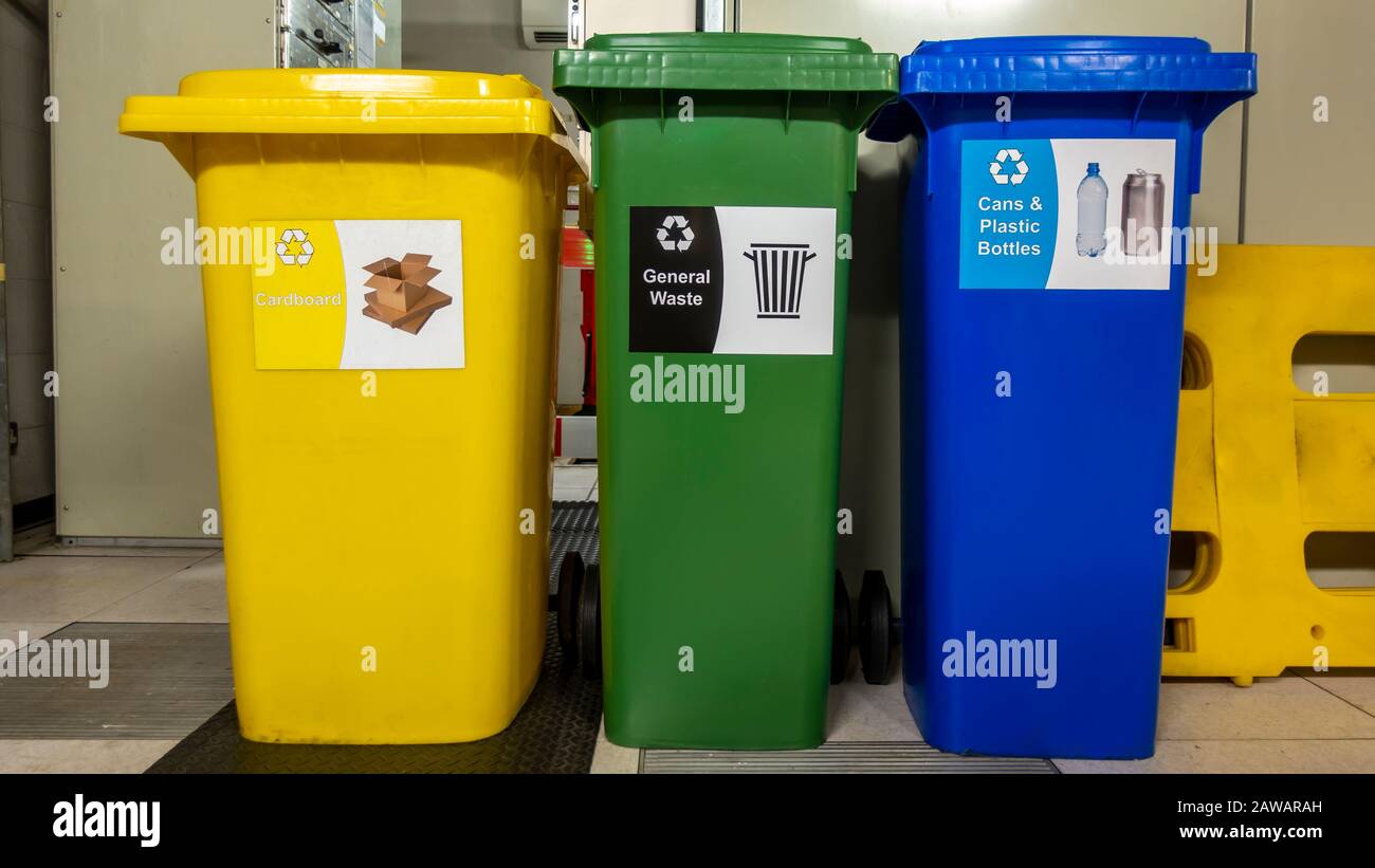 Yellow green and blue recycle wheelie bins in an industrial plant room ...