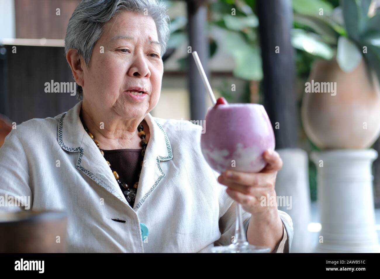 old asian elderly senior elder woman drinking berry smoothie milkshake at restaurant. mature ...